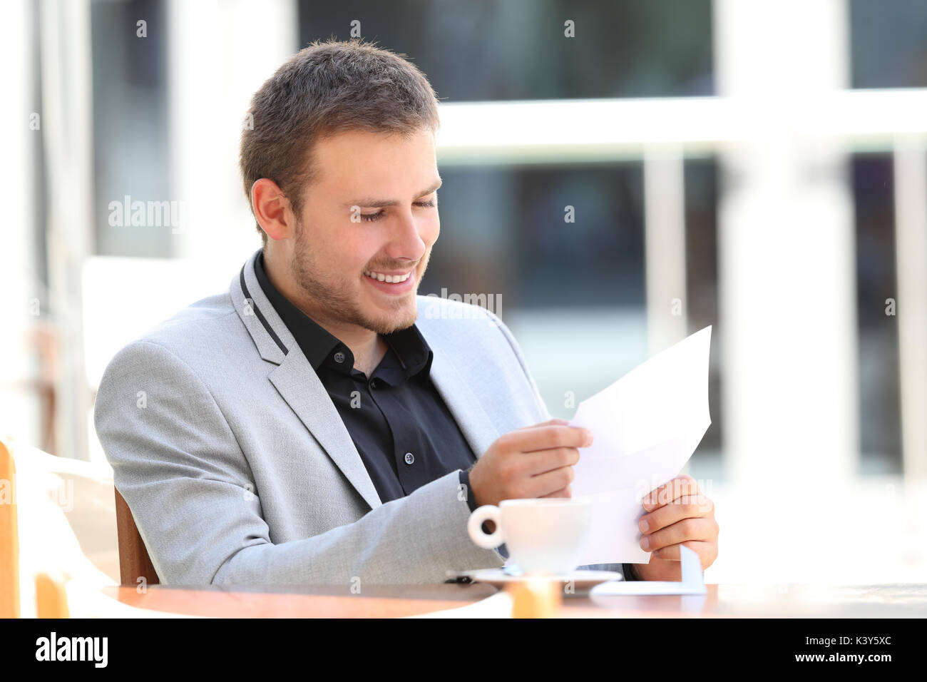Single happy executive reading a letter sitting in a bar Stock Photo ...