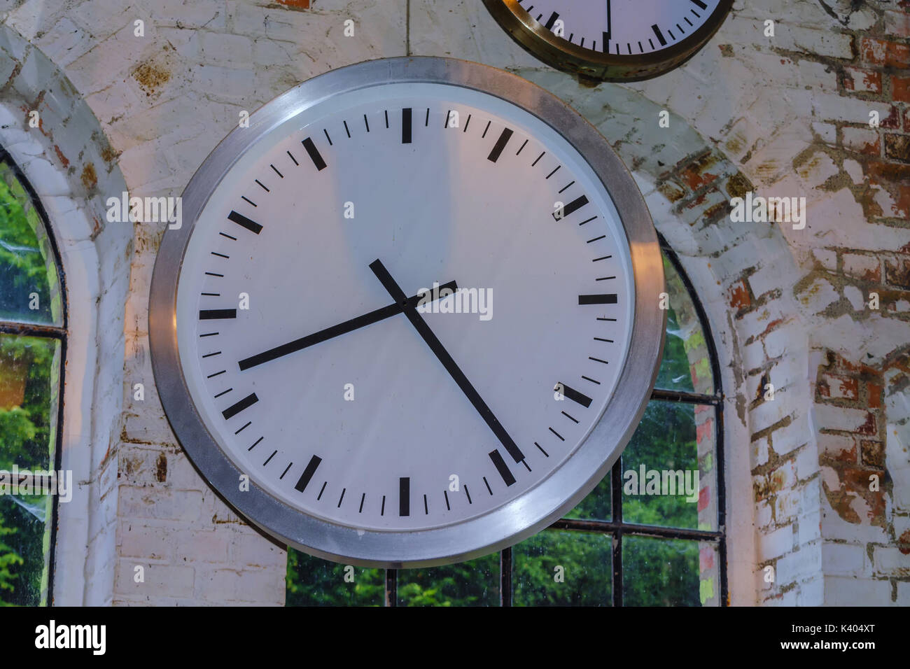 Large clock in front of the window in an industrial factory on a brick ...