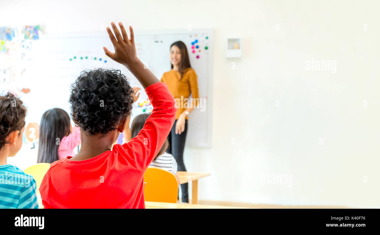 African American ethnicity kid hand up for answer question of teacher ...