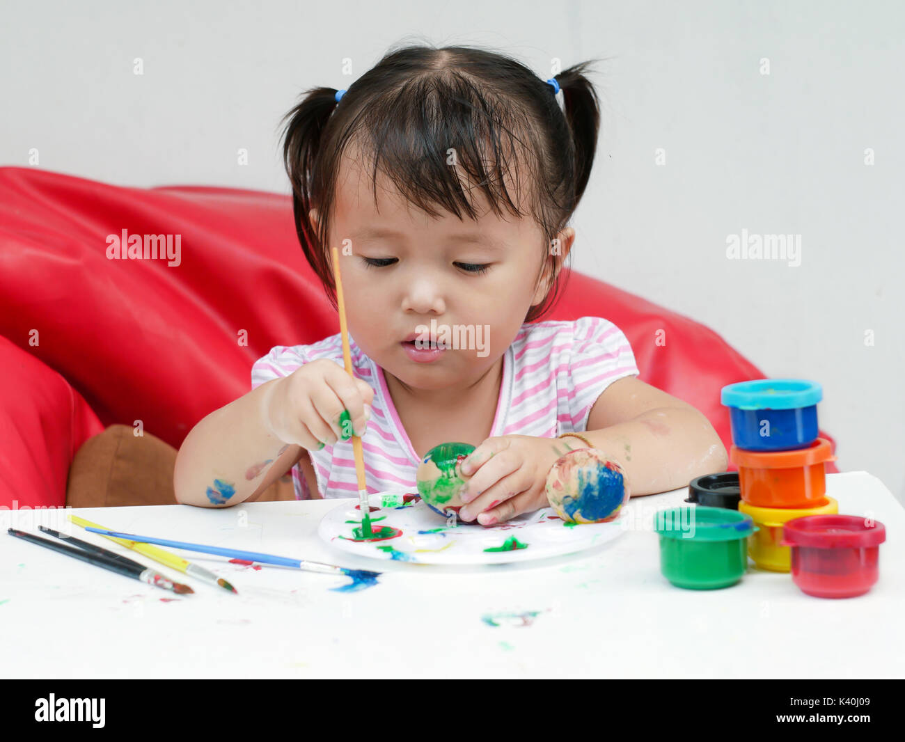 Little Girl Painting with paintbrush and colorful paints children ...