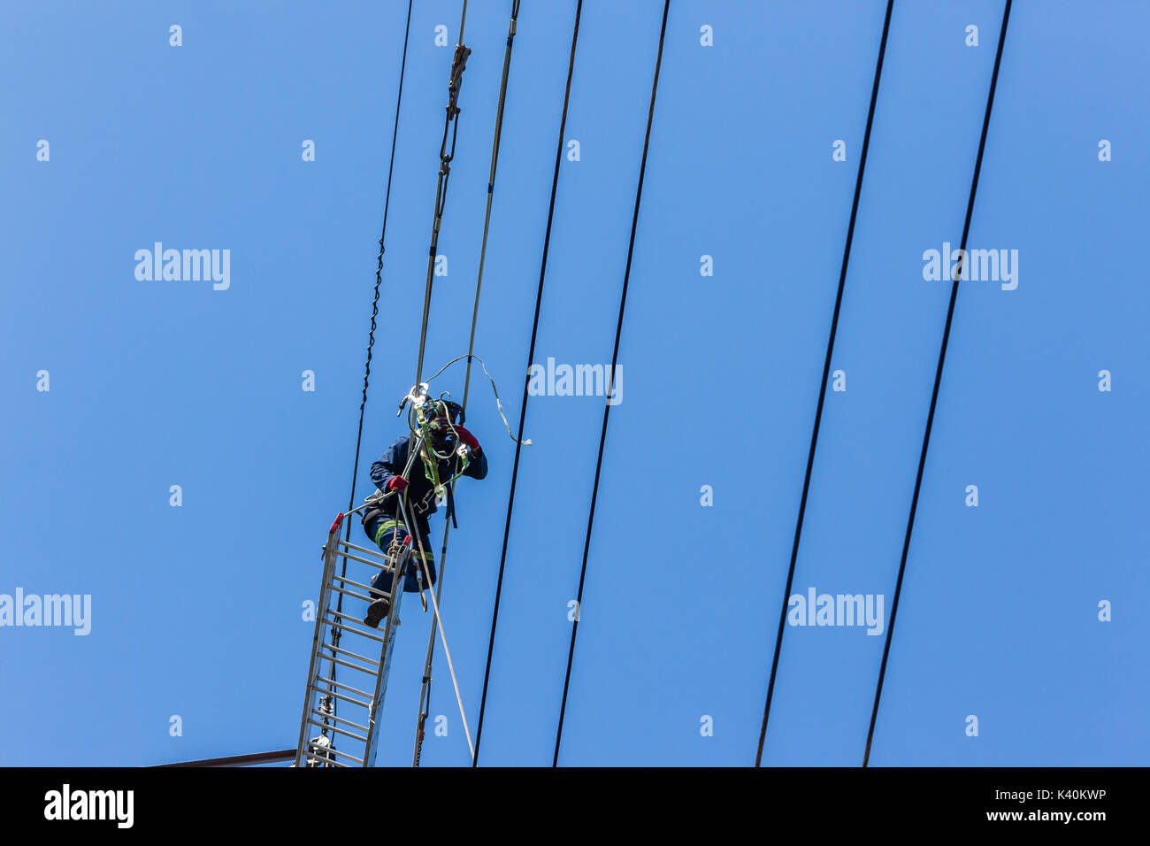 Electricians high up suspended on electrical steel tower installing new ...