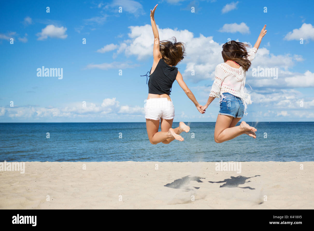 Happy friends holding hands jumping hi-res stock photography and images ...