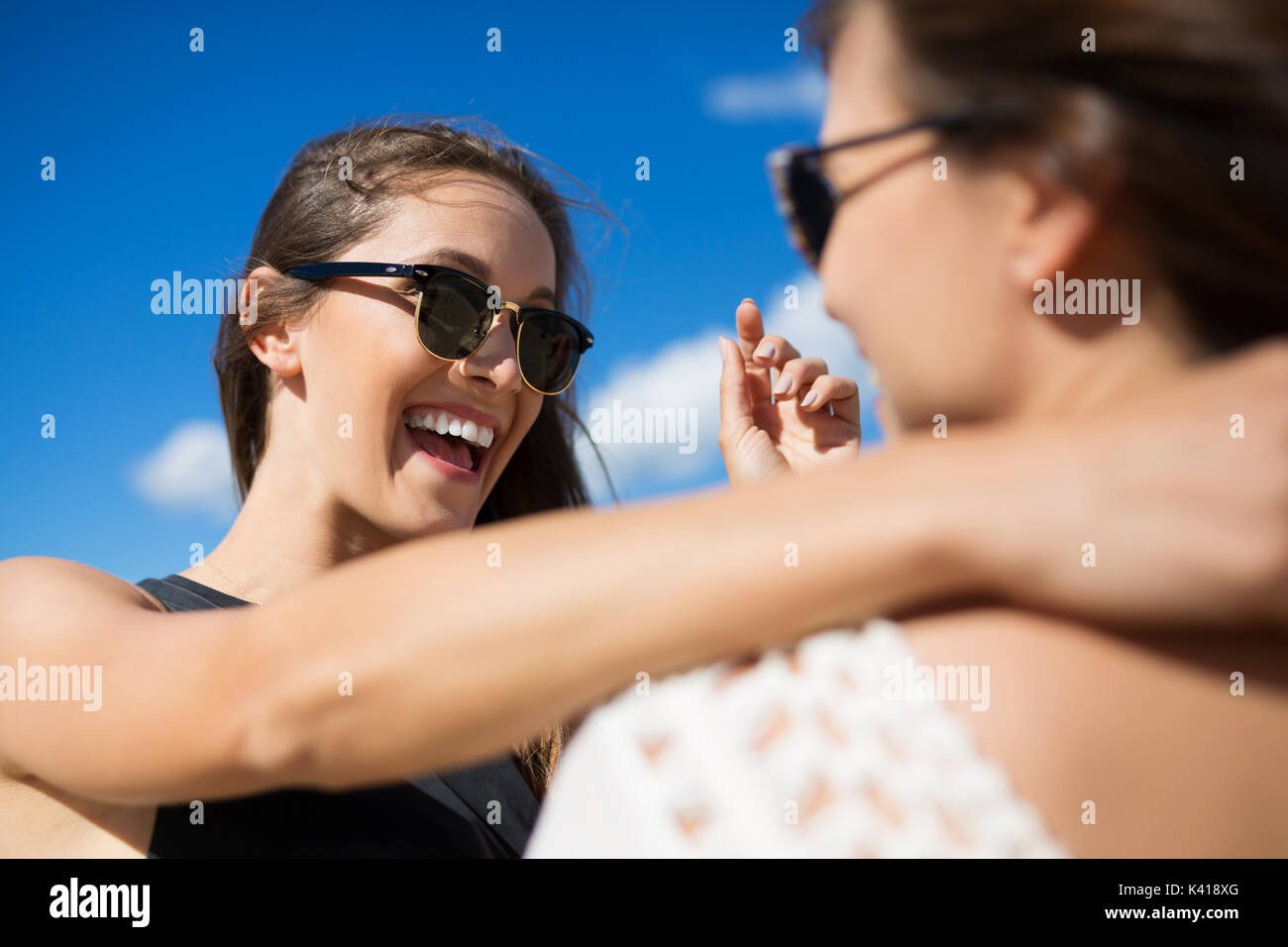 Portrait of young happy woman embracing female friend telling her ...