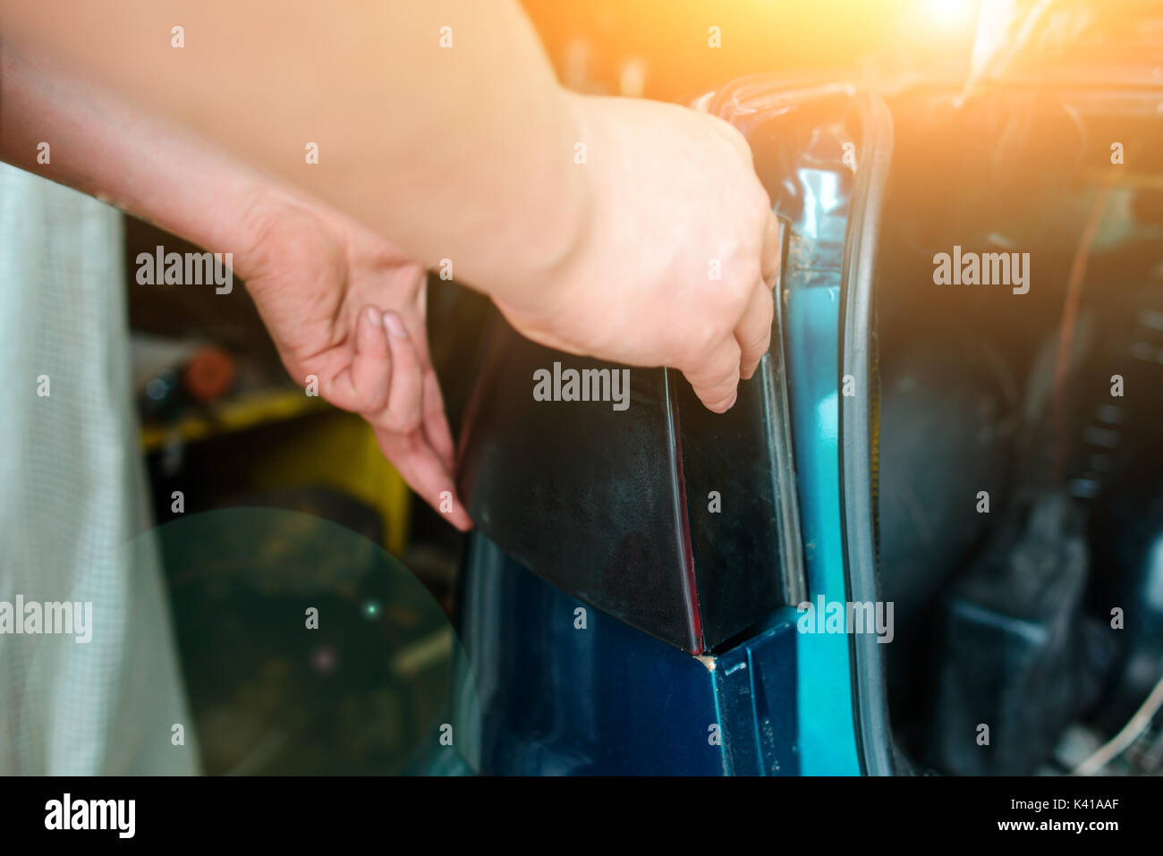 Closeup repairing of an broken blue car in garage by hands of machanic ...