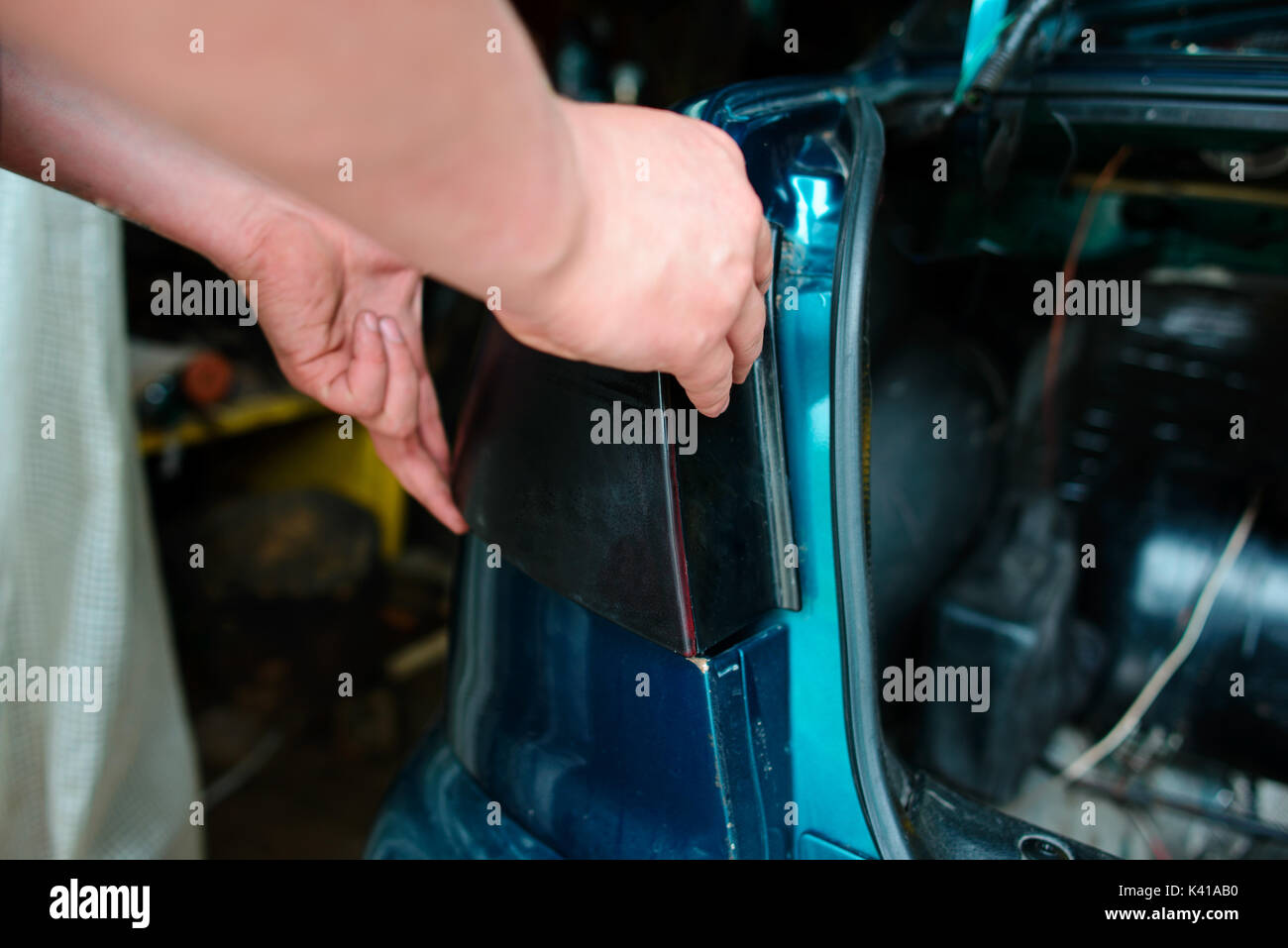 Closeup repairing of an broken blue car in garage by hands of machanic ...