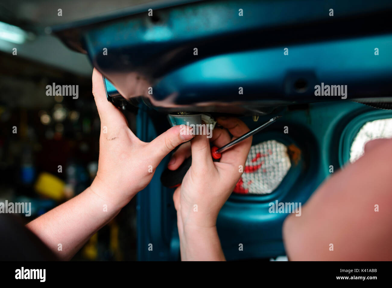 Closeup repairing of an broken blue car in garage by hands of machanic ...