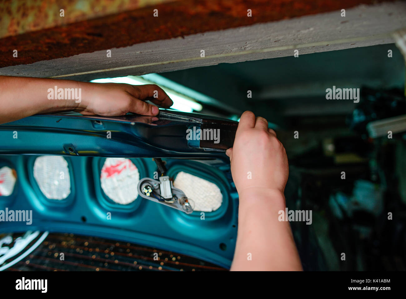 Closeup repairing of an broken blue car in garage by hands of machanic ...