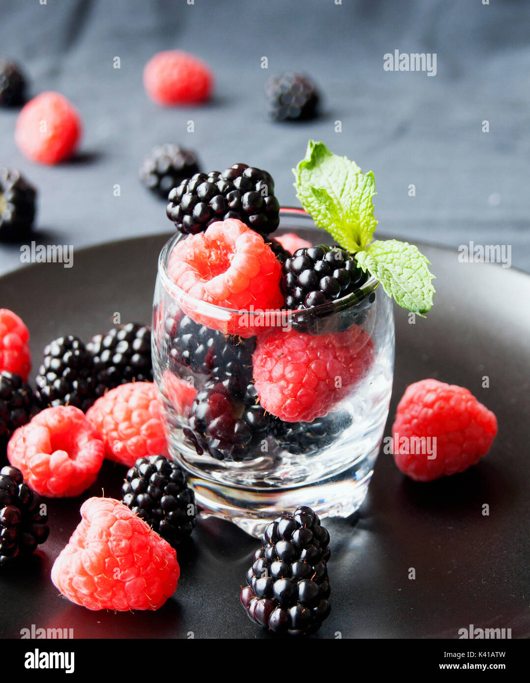 black berries and raspberries in a glass black background, selective ...