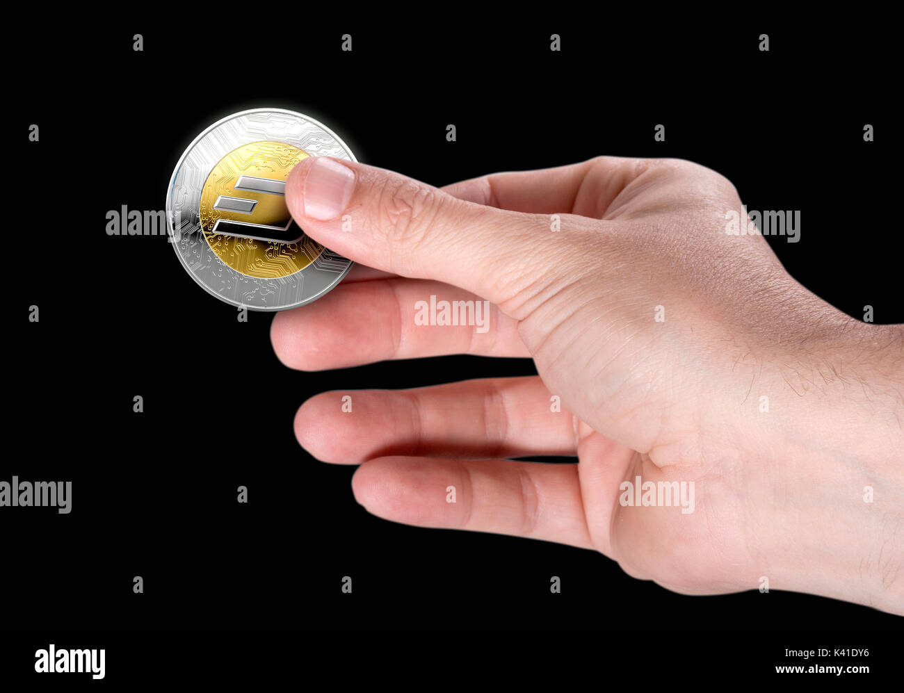 A male hand holding a physical dash cryptocurrency in gold and silver ...