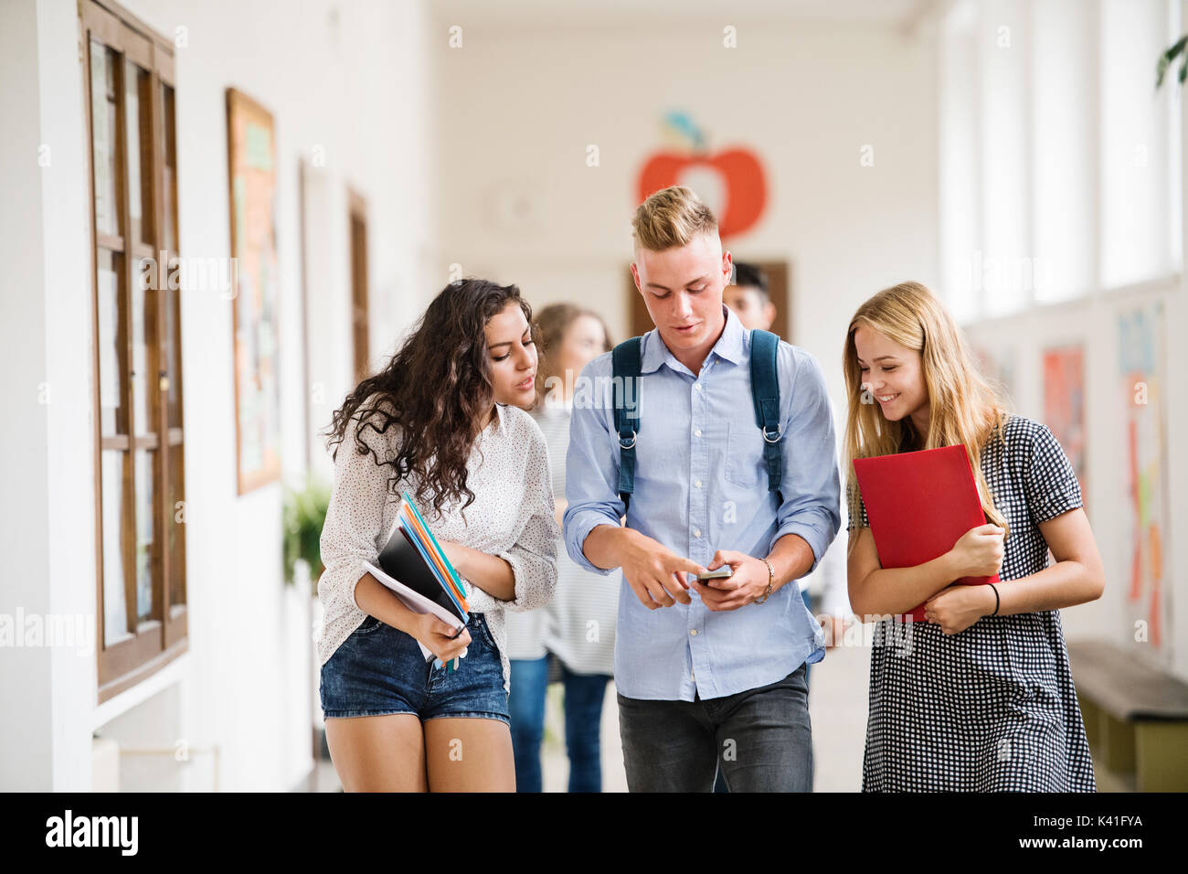 Teenage students walking in high school hall, talking Stock Photo - Alamy