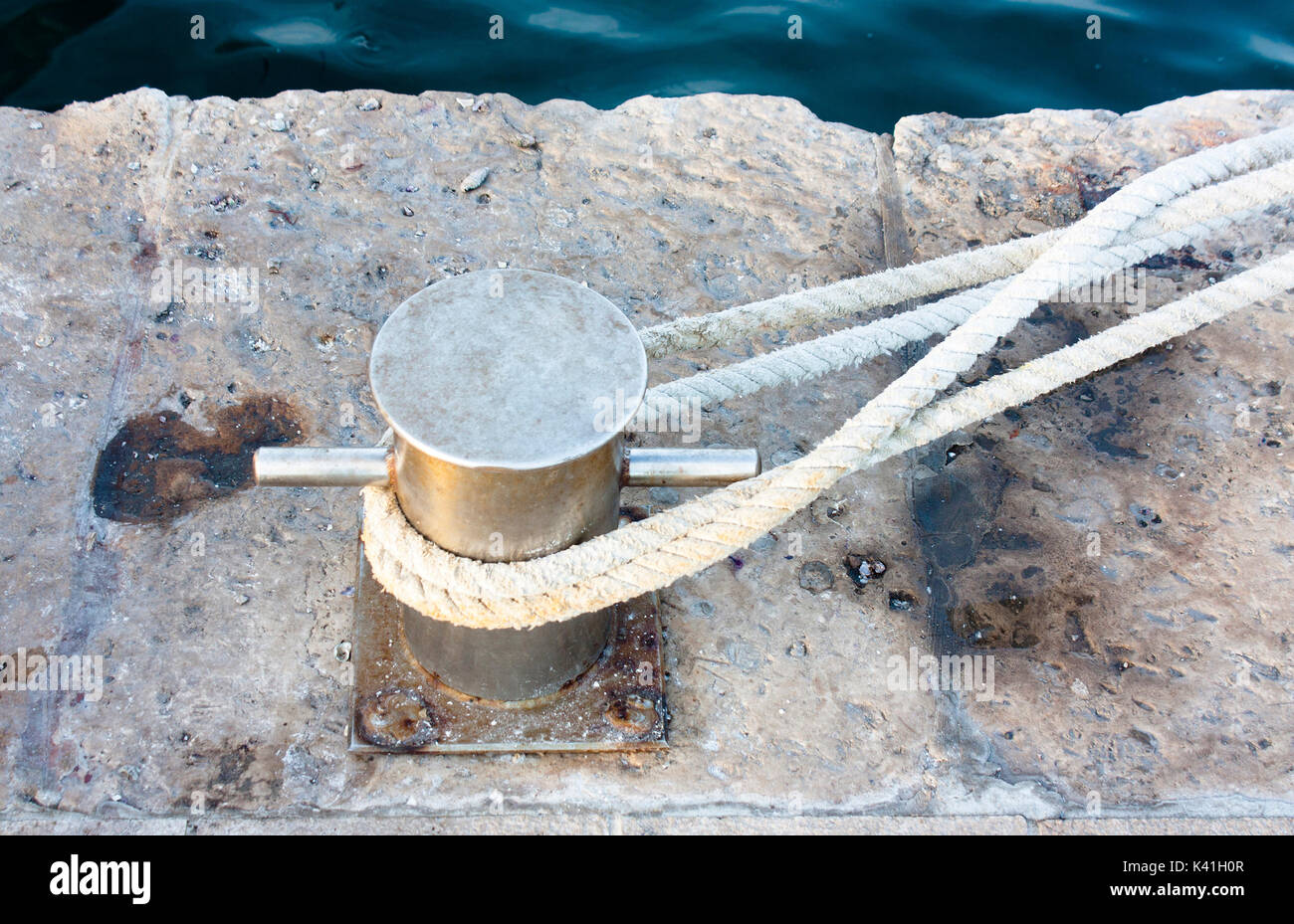 Dock bollard on the stone pier with ropes for sailboat Stock Photo - Alamy