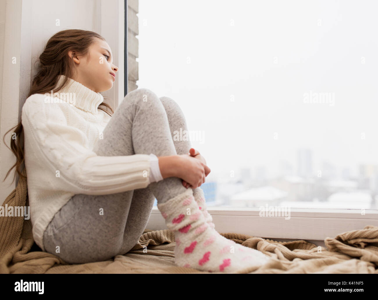 sad girl sitting on sill at home window in winter Stock Photo - Alamy