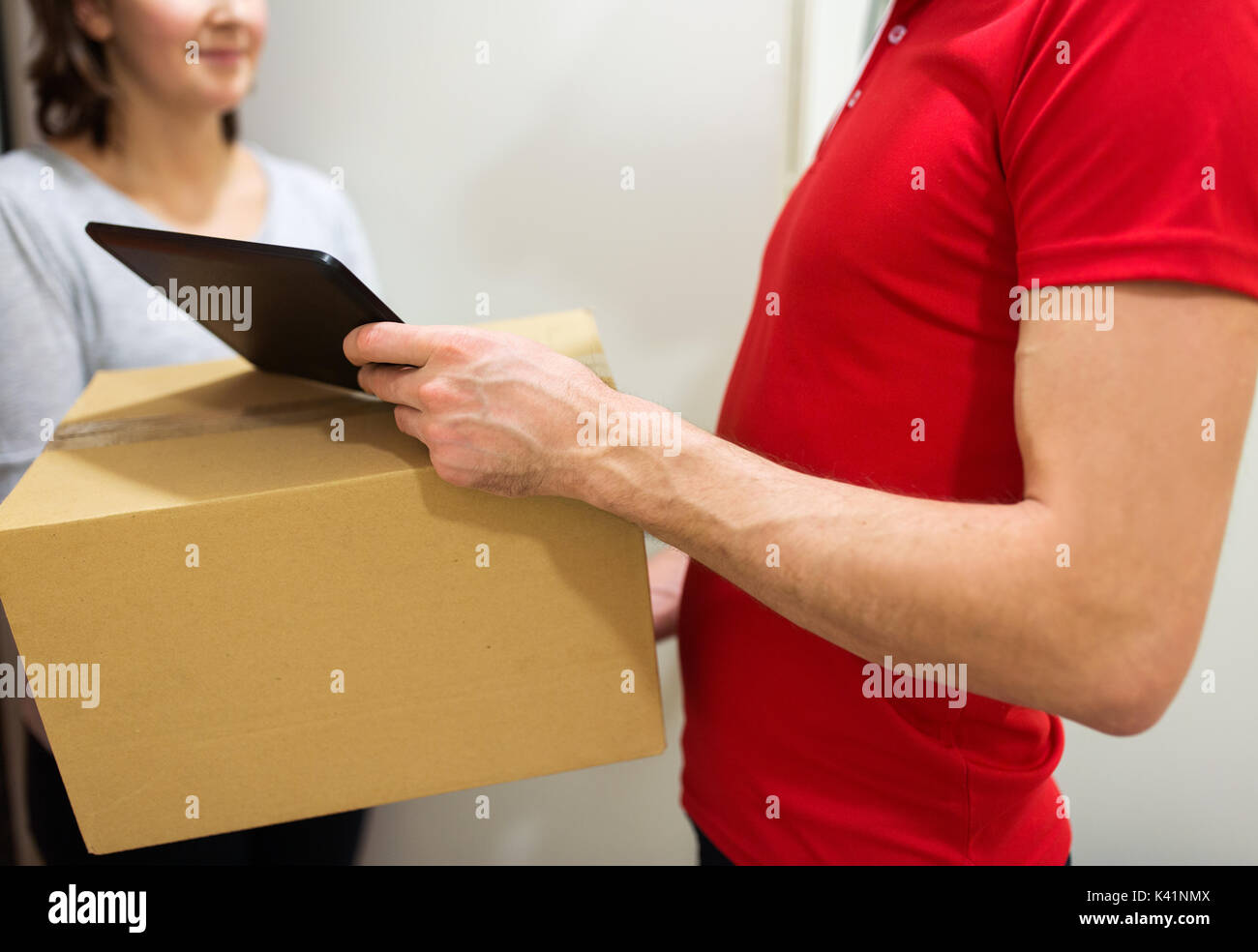 delivery man with box, tablet pc and customer Stock Photo - Alamy