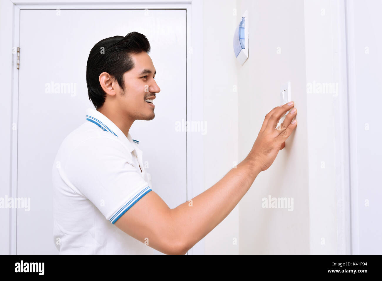 Handsome asian man turning off the light with wall switch in the home ...