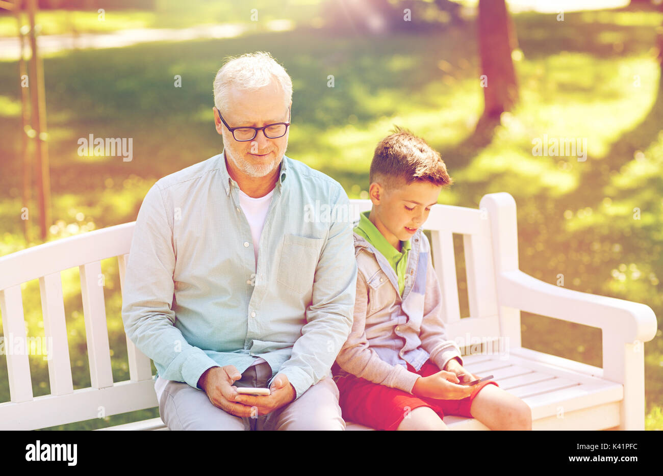 old man and boy with smartphones at summer park Stock Photo - Alamy