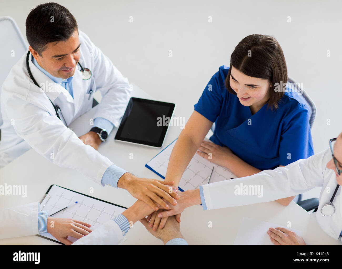 group of doctors holding hands together at table Stock Photo - Alamy