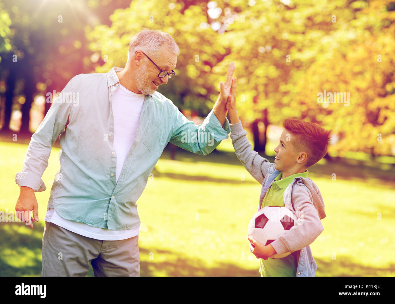old man and boy with soccer ball making high five Stock Photo - Alamy