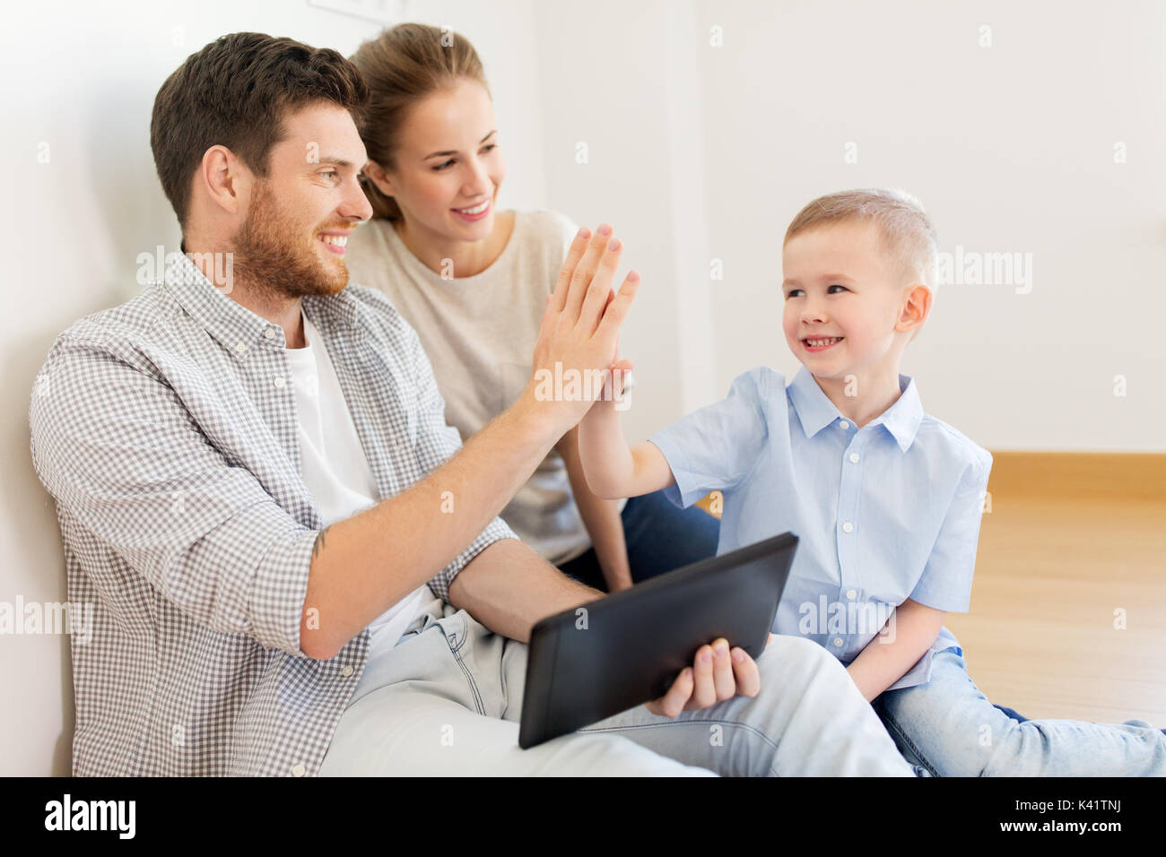 family with tablet pc at new home making high five Stock Photo - Alamy