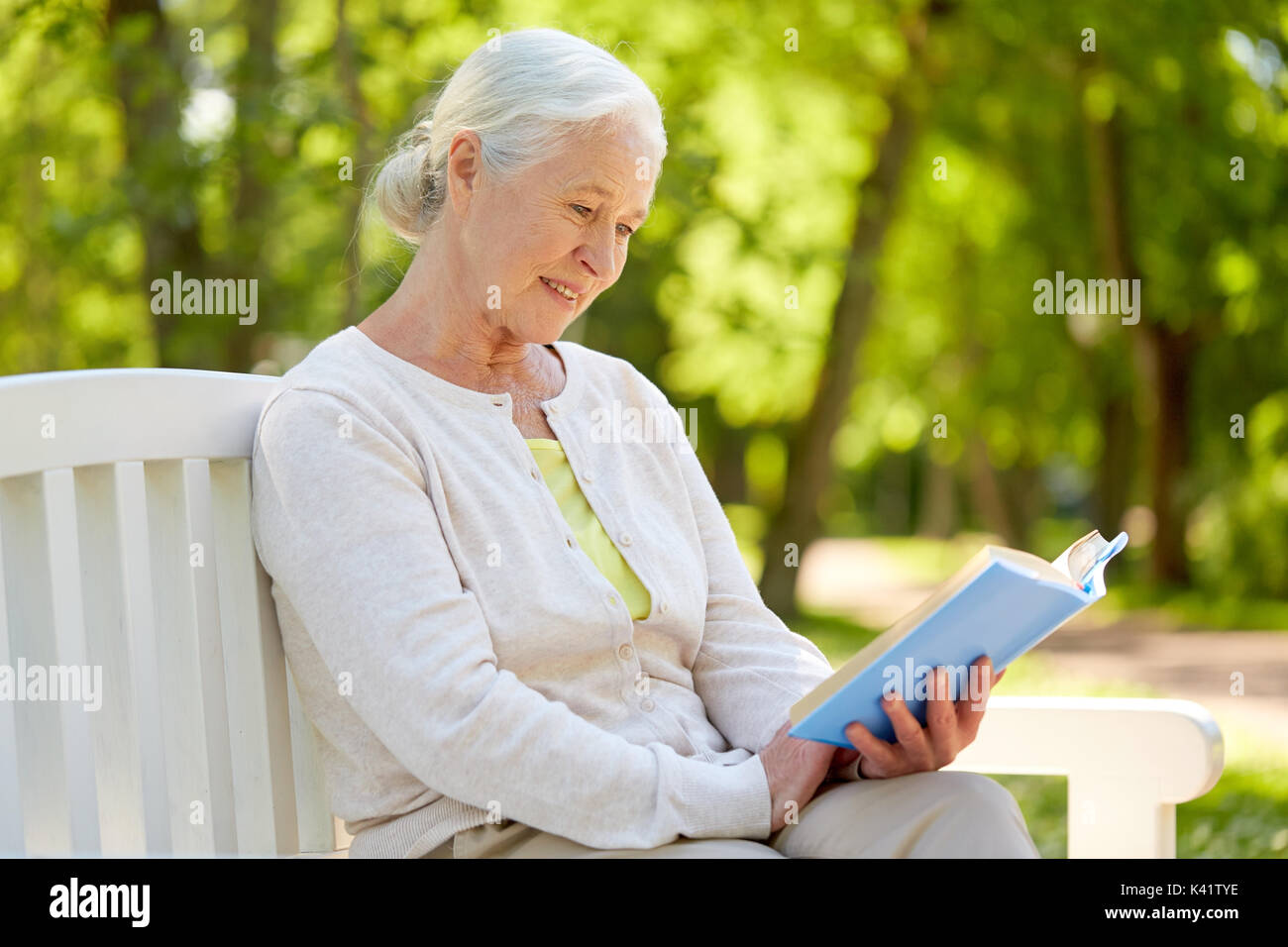 happy senior woman reading book at summer park Stock Photo - Alamy