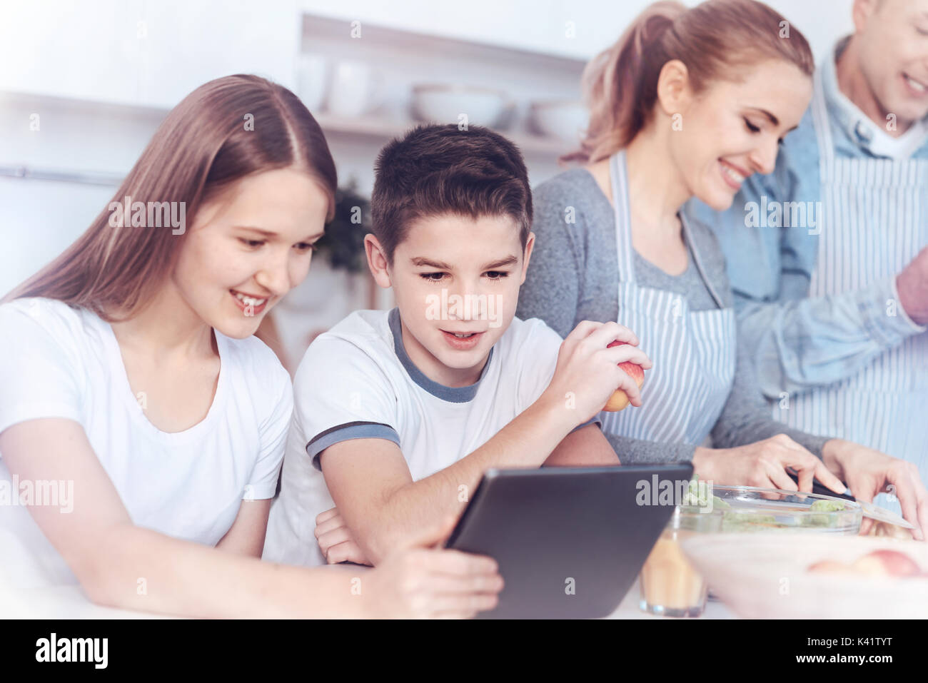Charming kids playing on digital tablet while parents cooking Stock ...
