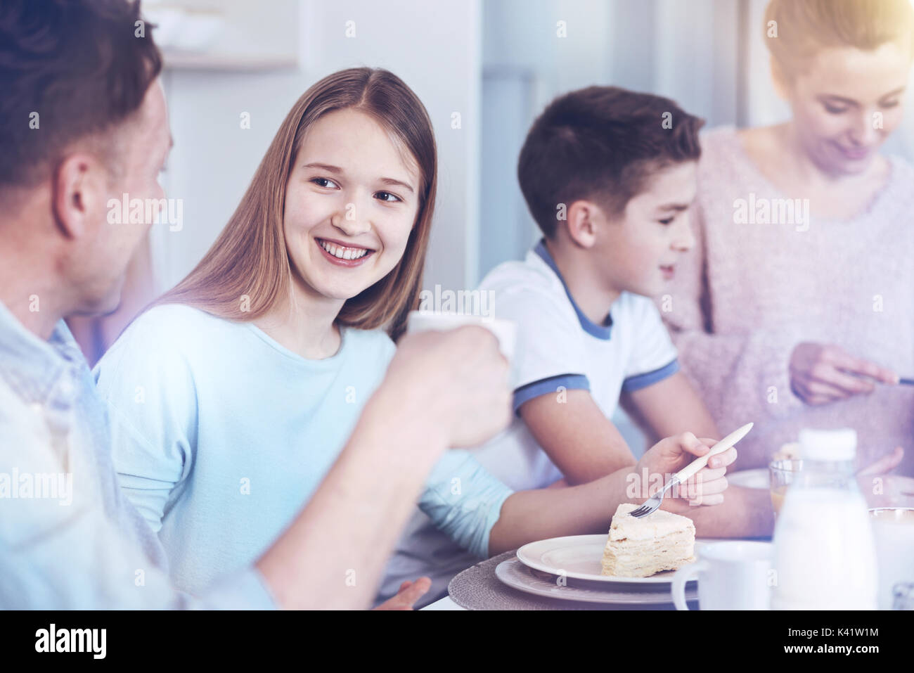Cheerful girl talking to father while eating piece of cake Stock Photo ...