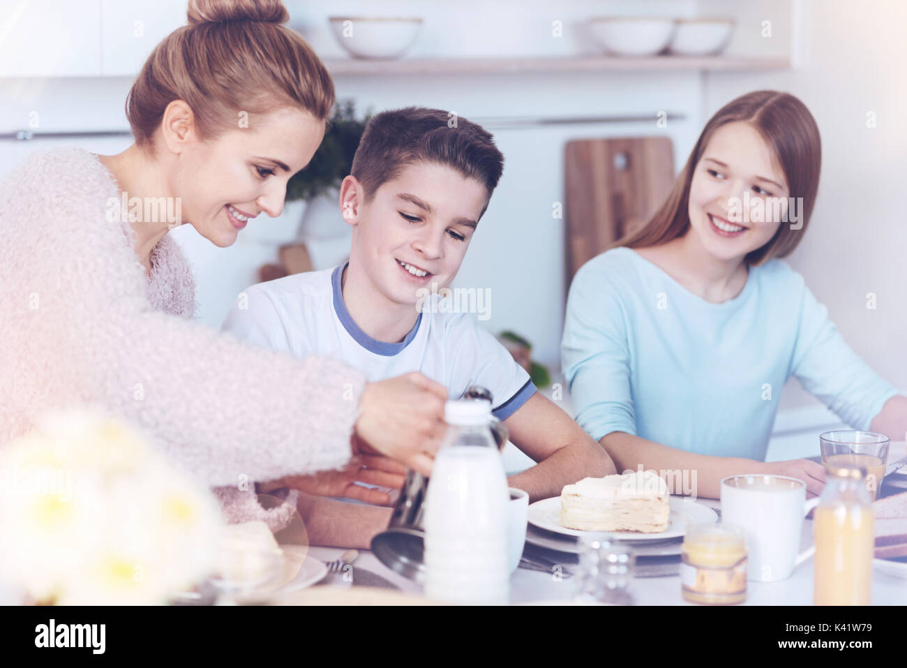 Loving mother taking care of children during family breakfast time ...