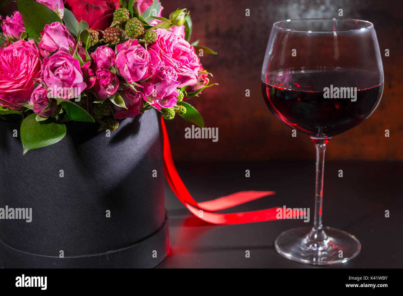 Bouquet of pink and red roses and red ribbon in a circular black box ...