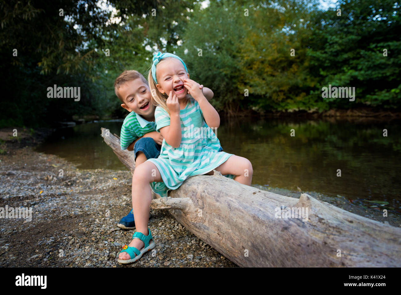 Adorable siblings playing silly by a river, summer outdoors wanderlust ...