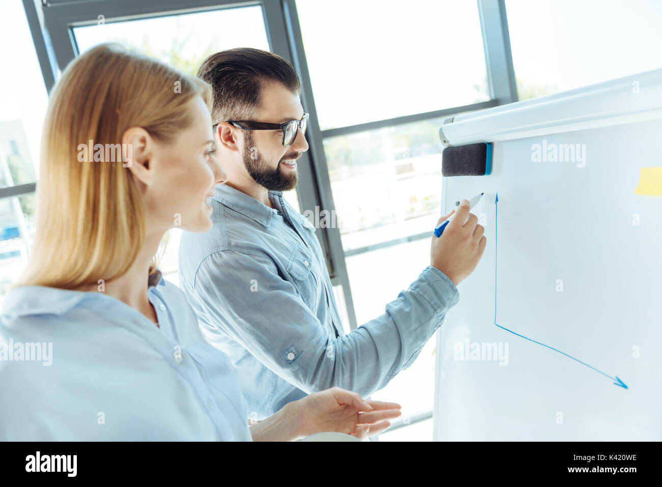 Cheerful man drawing a graph on a whiteboard Stock Photo - Alamy