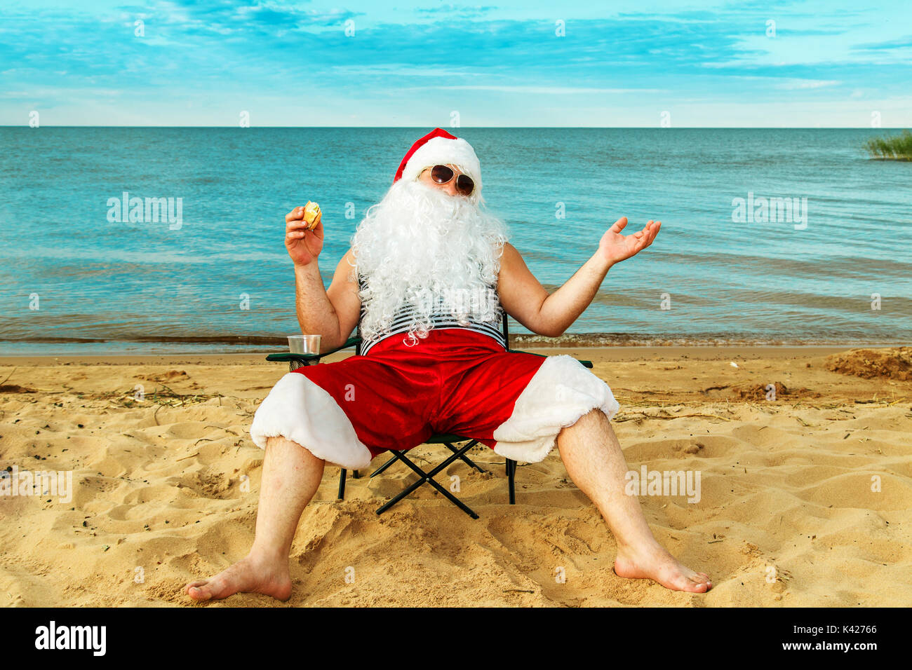 Santa Claus on the beach eating a hamburger. The concept of unhealthy ...