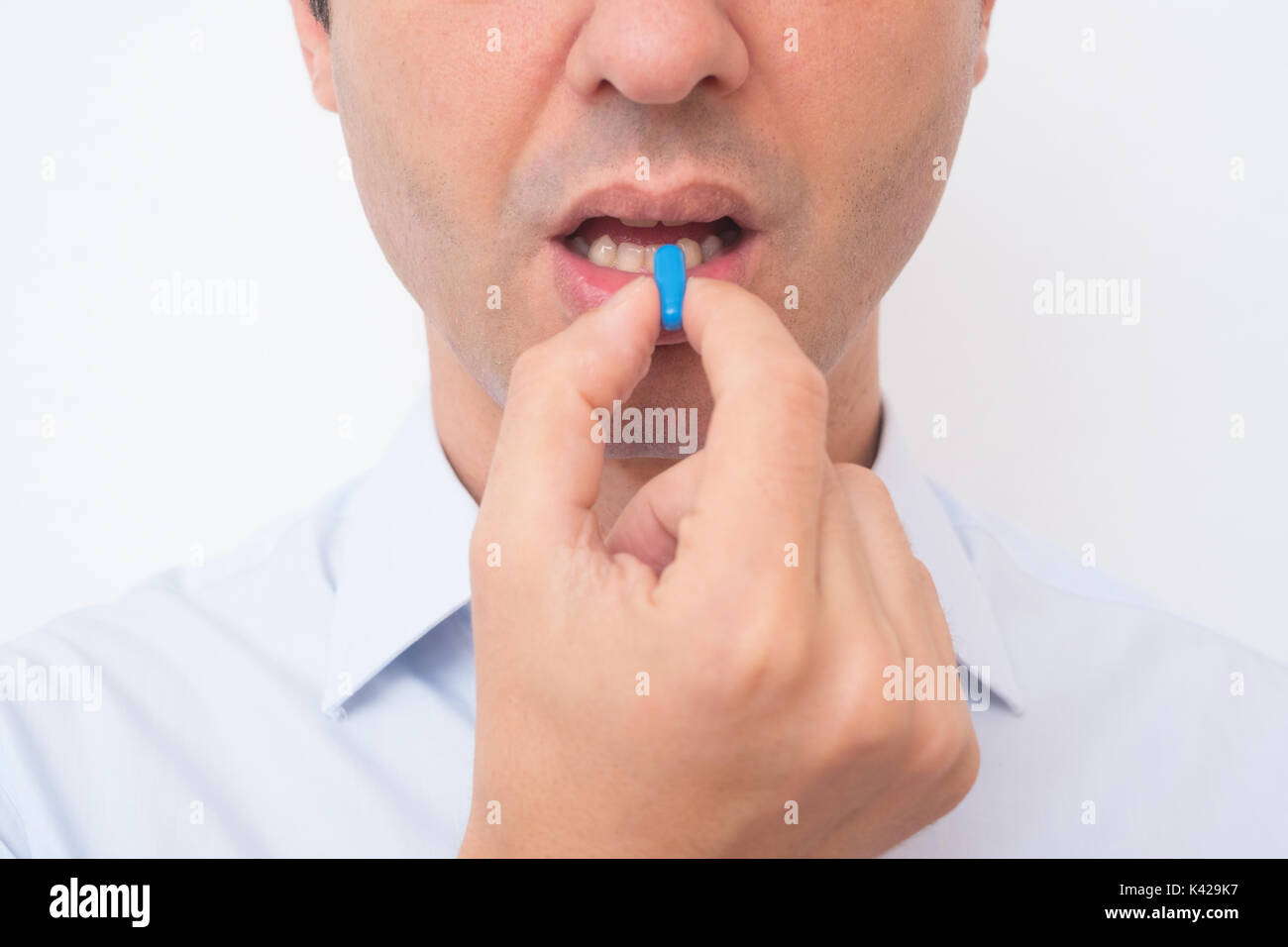 Head of sick man eating blue medicine pill Stock Photo - Alamy