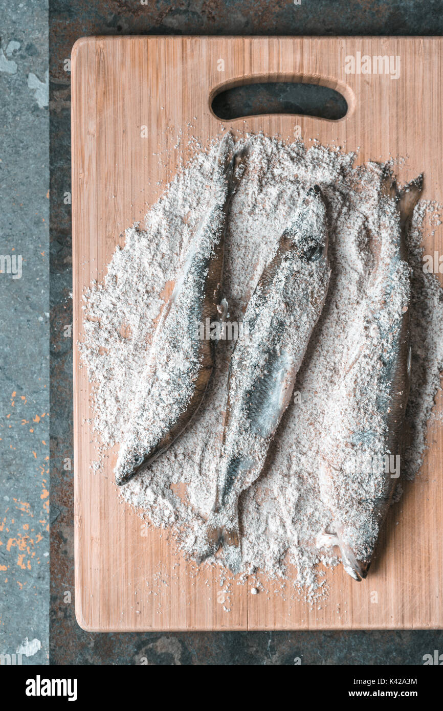 Fish on a flour on a cutting board top view vertical Stock Photo - Alamy