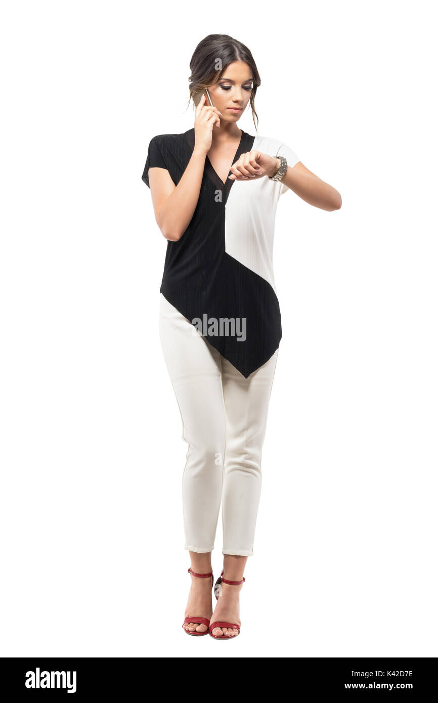 Busy business woman checking time on wrist watch talking on the mobile ...