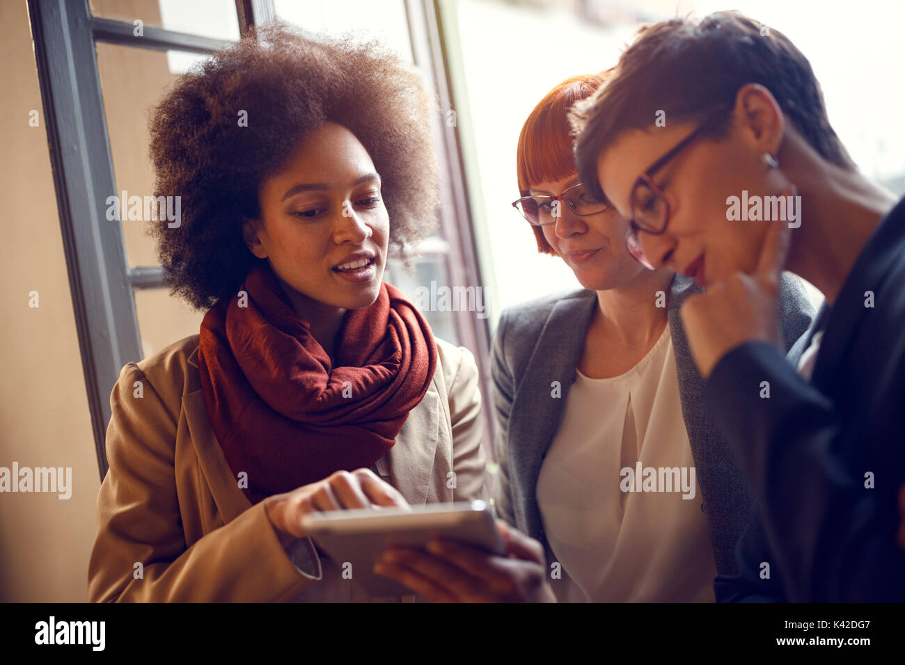 Females planning project by window in office Stock Photo - Alamy
