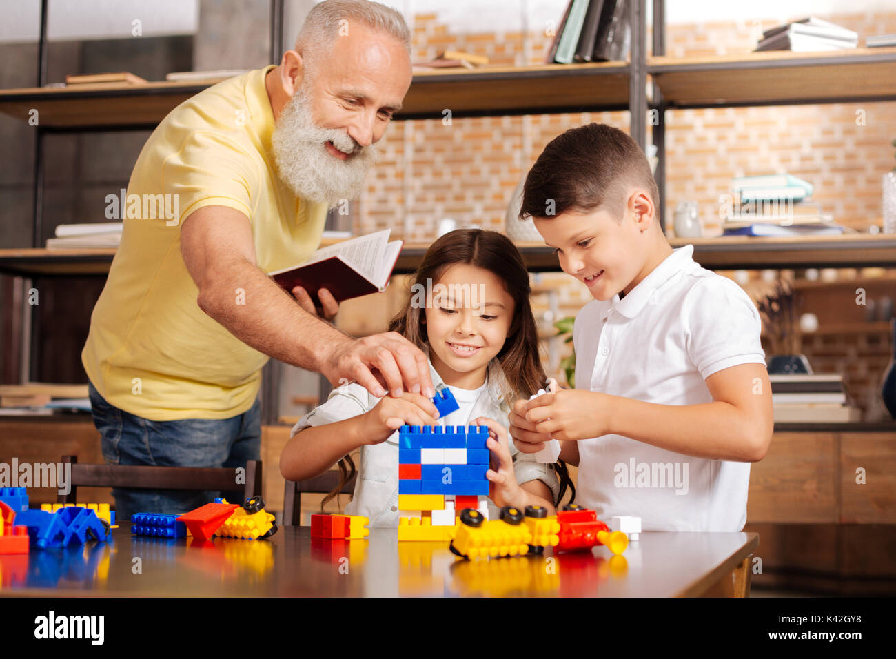 Grandfather helping grandchildren build a tower with construction set ...