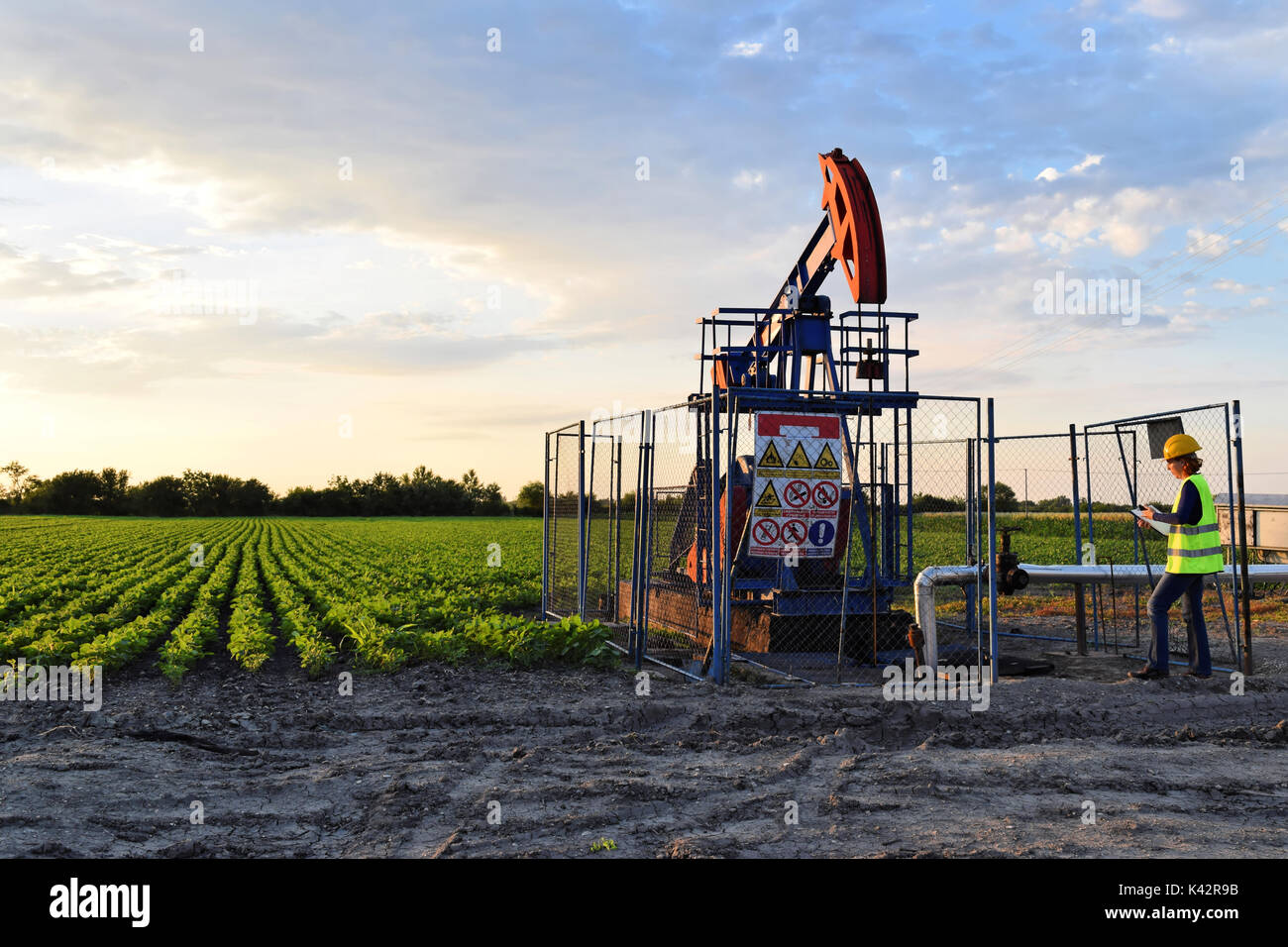 A female petroleum engineer at work on an European oil well during dusk ...
