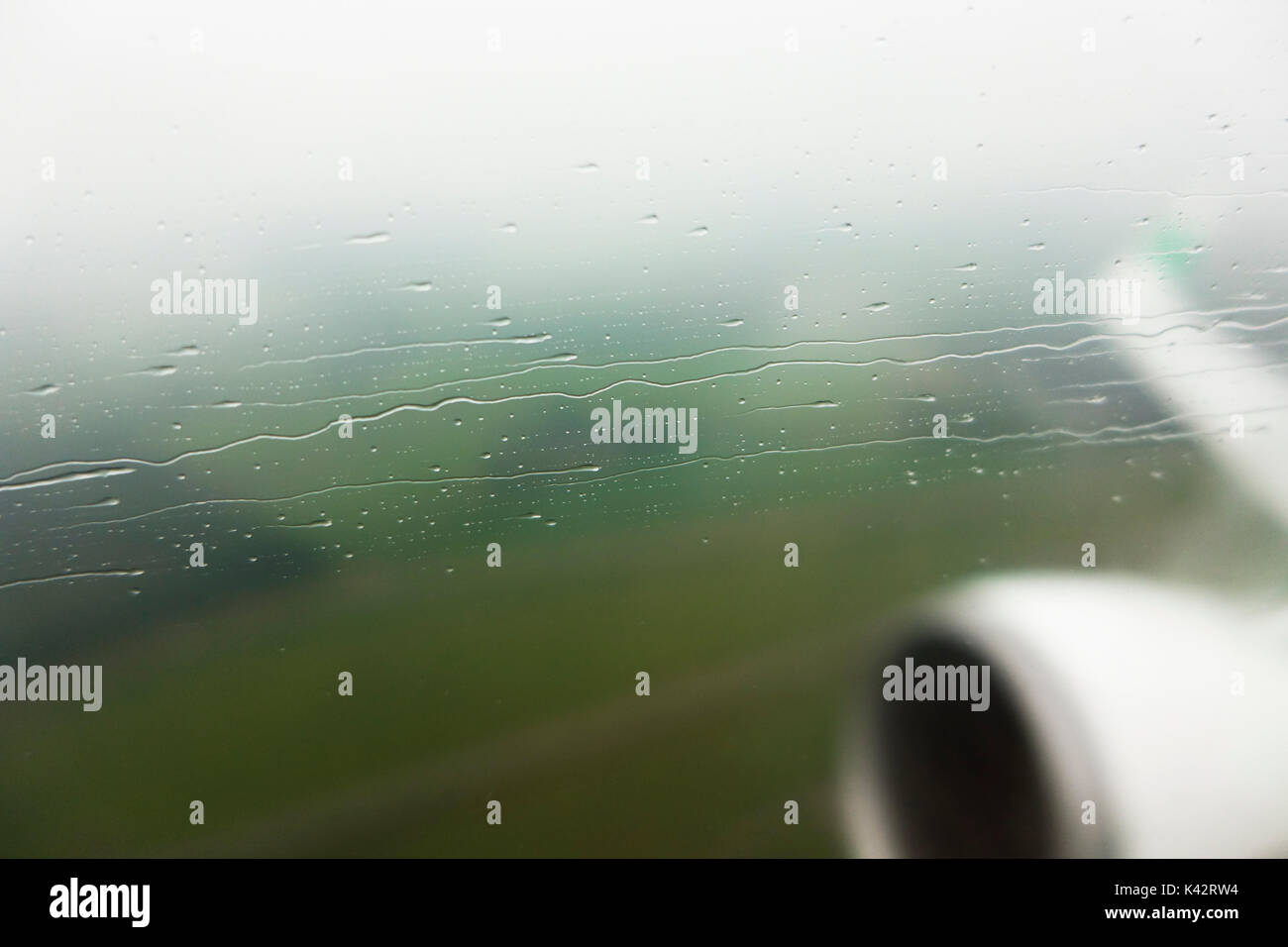 Rain on window. Wing and motor of an airplane seen from airplane window ...