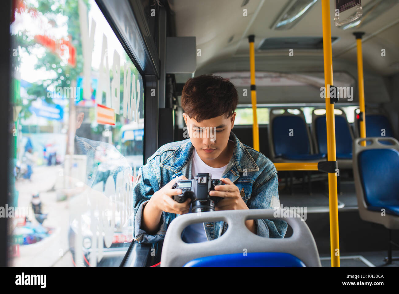 Asian male tourist photographing the city from the window of the bus ...