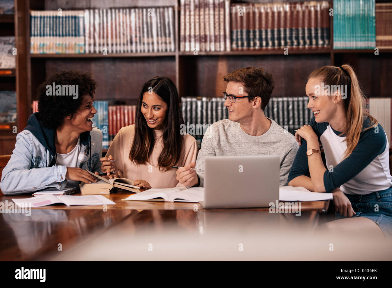 Group of students sitting at table in library and studying together ...