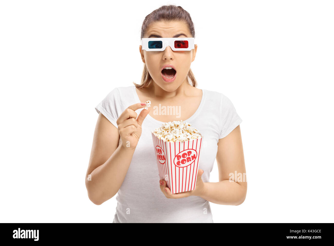 Scared girl with 3D glasses and popcorn looking at the camera isolated ...