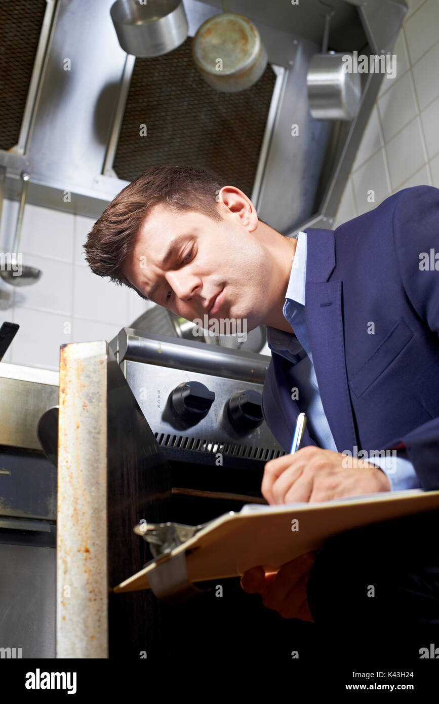 Health Inspector Looking At Oven In Commercial Kitchen Stock Photo - Alamy