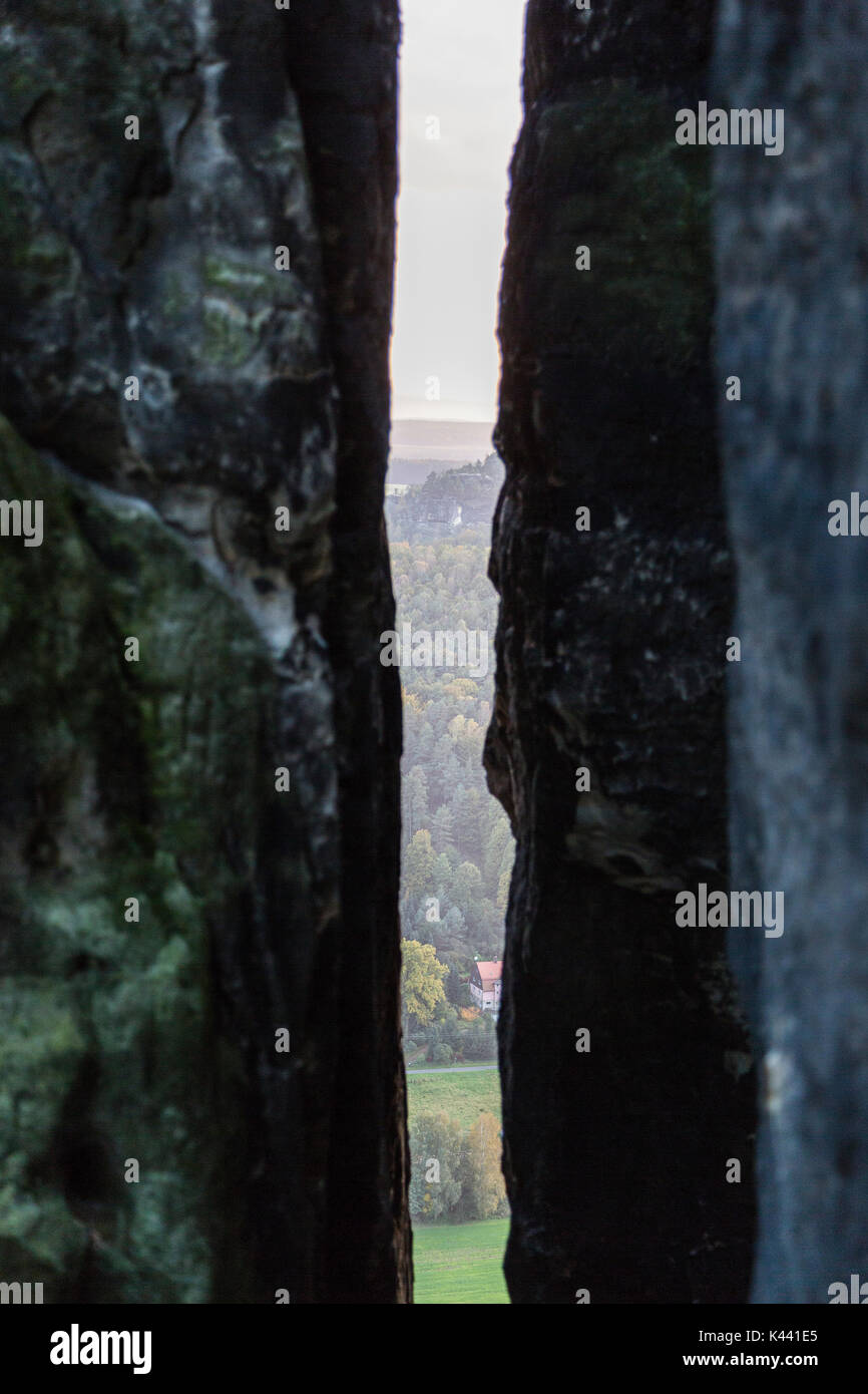 A narrow dark long gap between two stony cliffs, in which a wild green ...