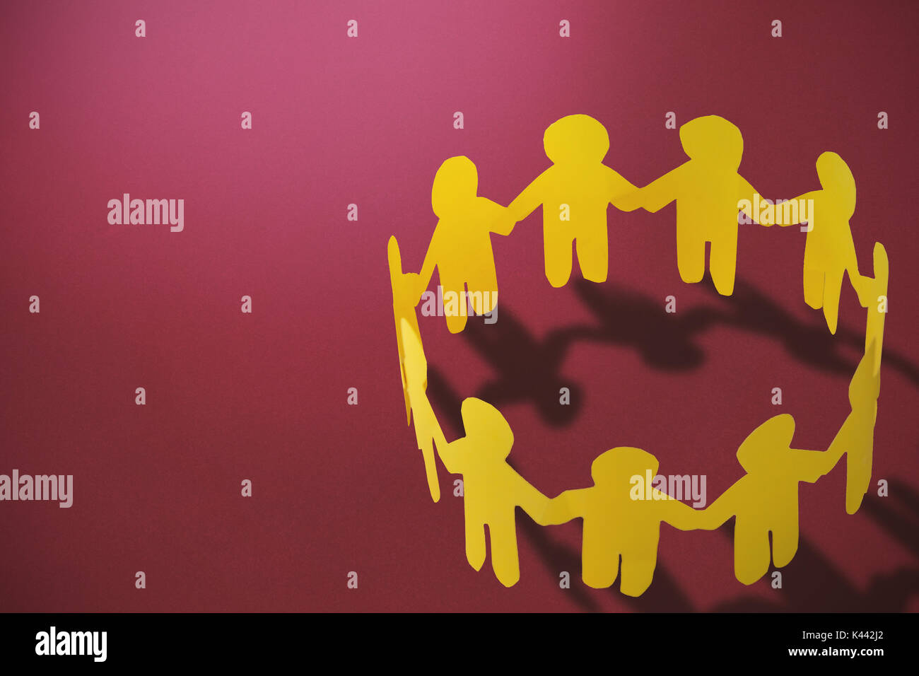 group of yellow little person holding hands against red background ...