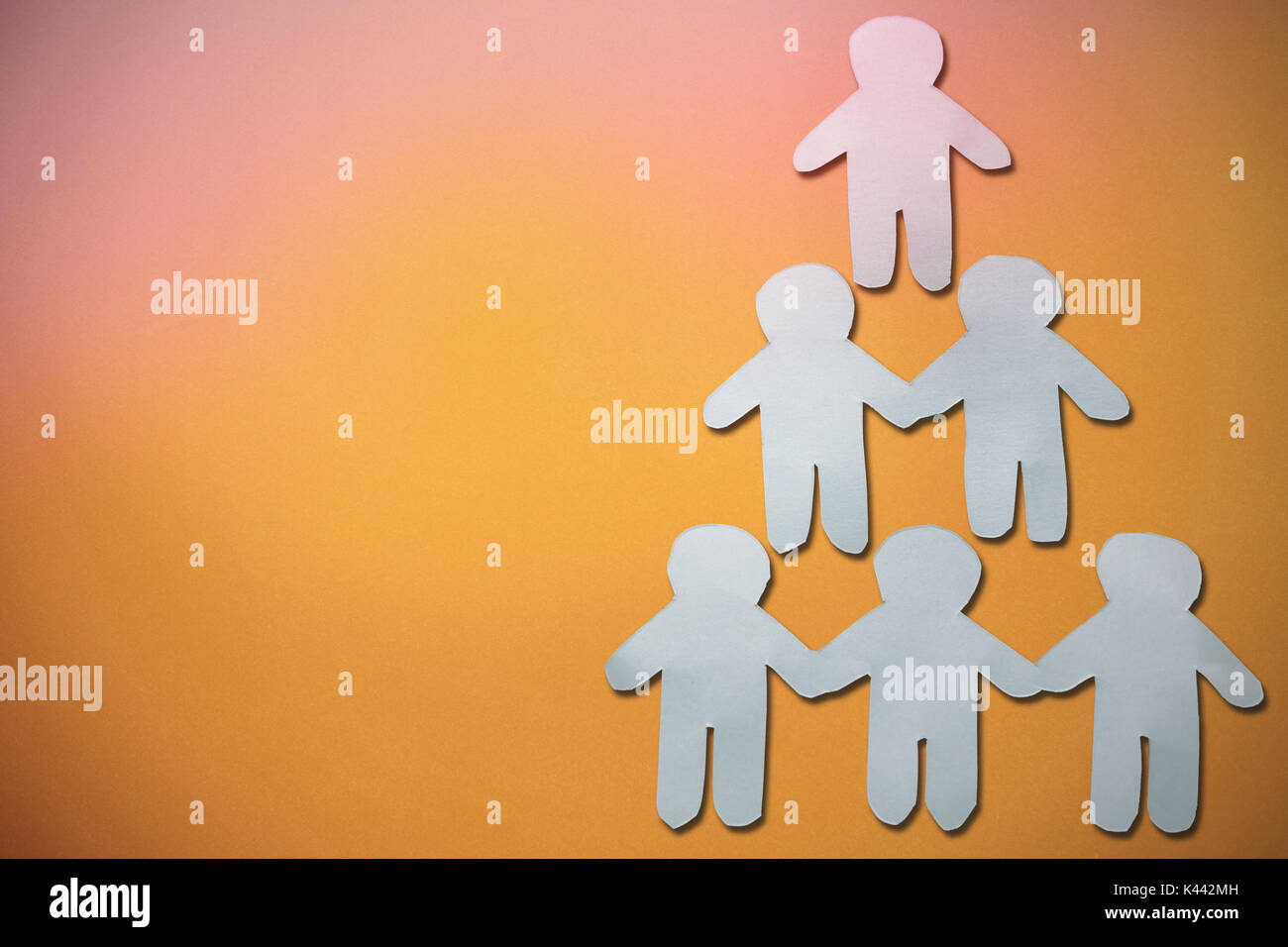 Pyramid of Little grey person against orange background Stock Photo - Alamy