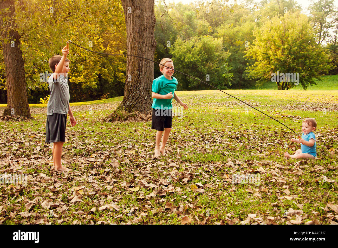 two boys playing jump rope with their baby brother Stock Photo - Alamy