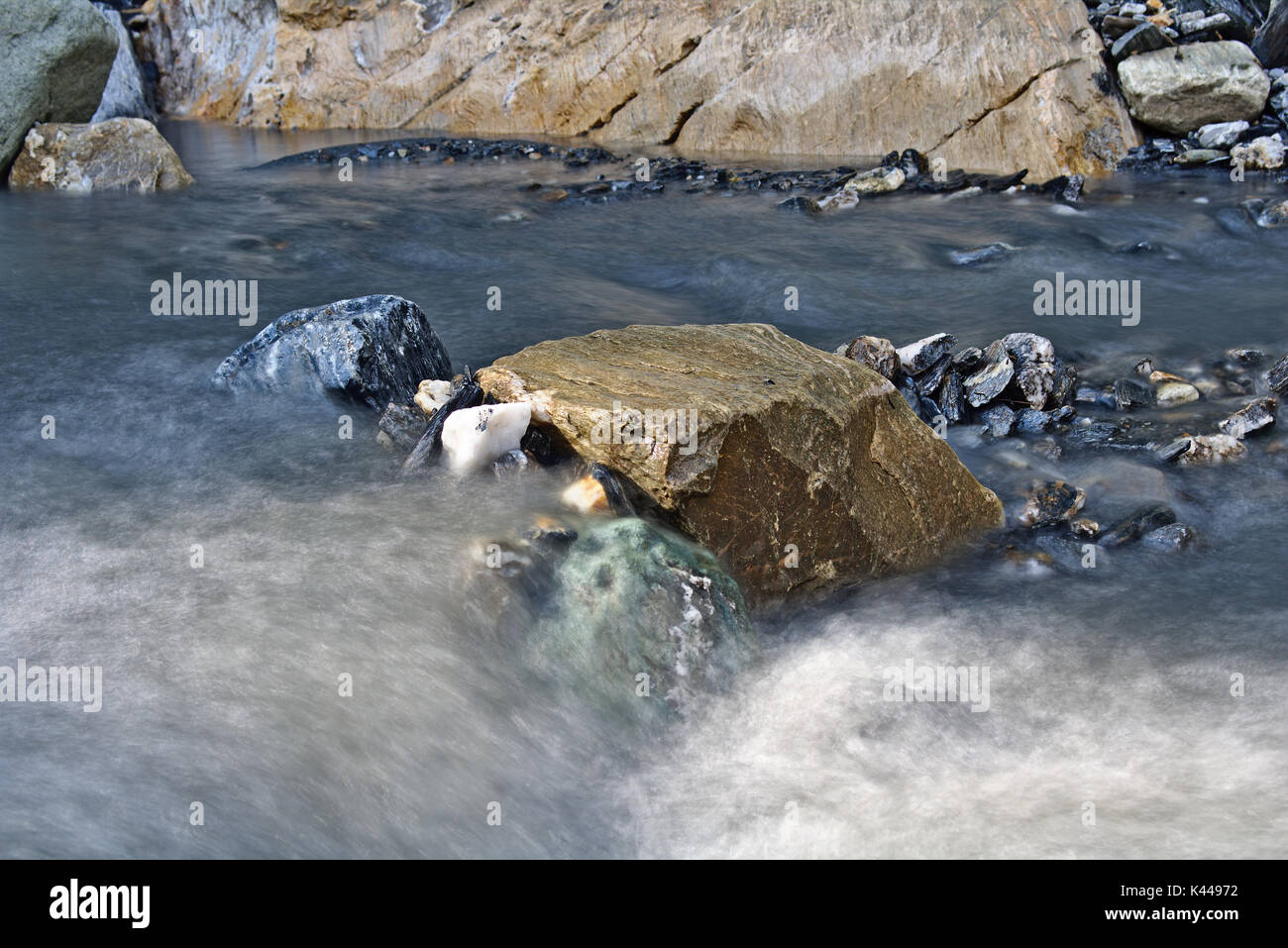 Boulders in a small mountain stream surrounded by smooth flowing water ...