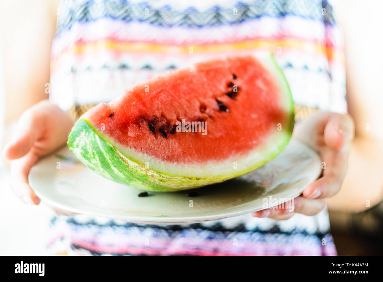 Watermelon background. Girl in a colorful summer shirt holding a plate ...