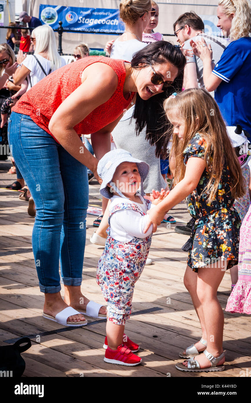 Little girl, 4-5 years, helping her baby sister to stand outside in ...