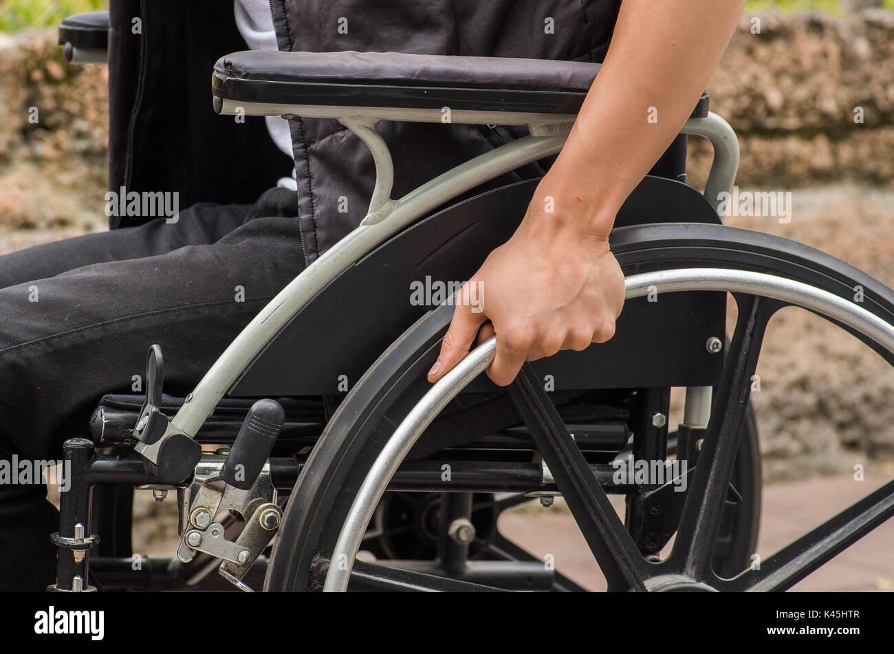 Close-up of male hand on wheel of wheelchair during walk in park Stock ...