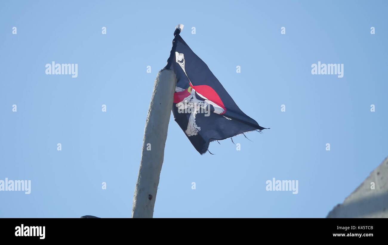 Jolly Roger Pirate flag develops against the blue sky Stock Photo - Alamy